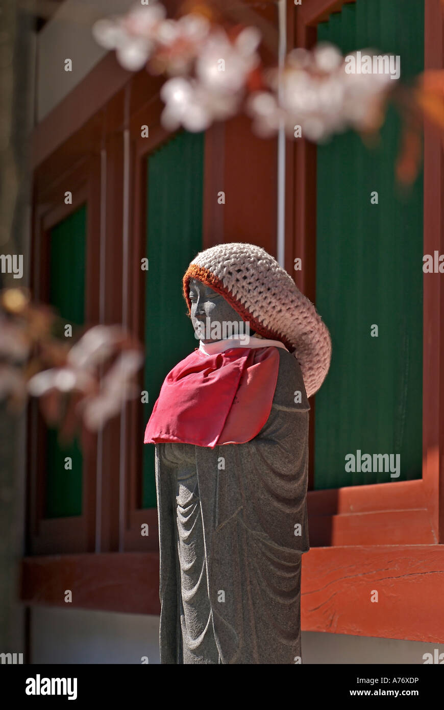 Jizo carving with bib and hat framed by cherry blossom KoyaSan Wakayama ...