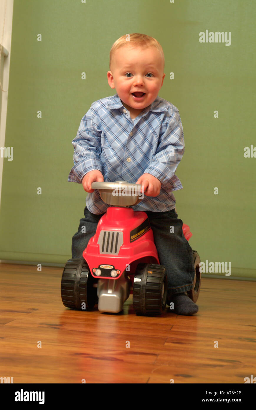 Little boy riding on toy car indoors Stock Photo - Alamy