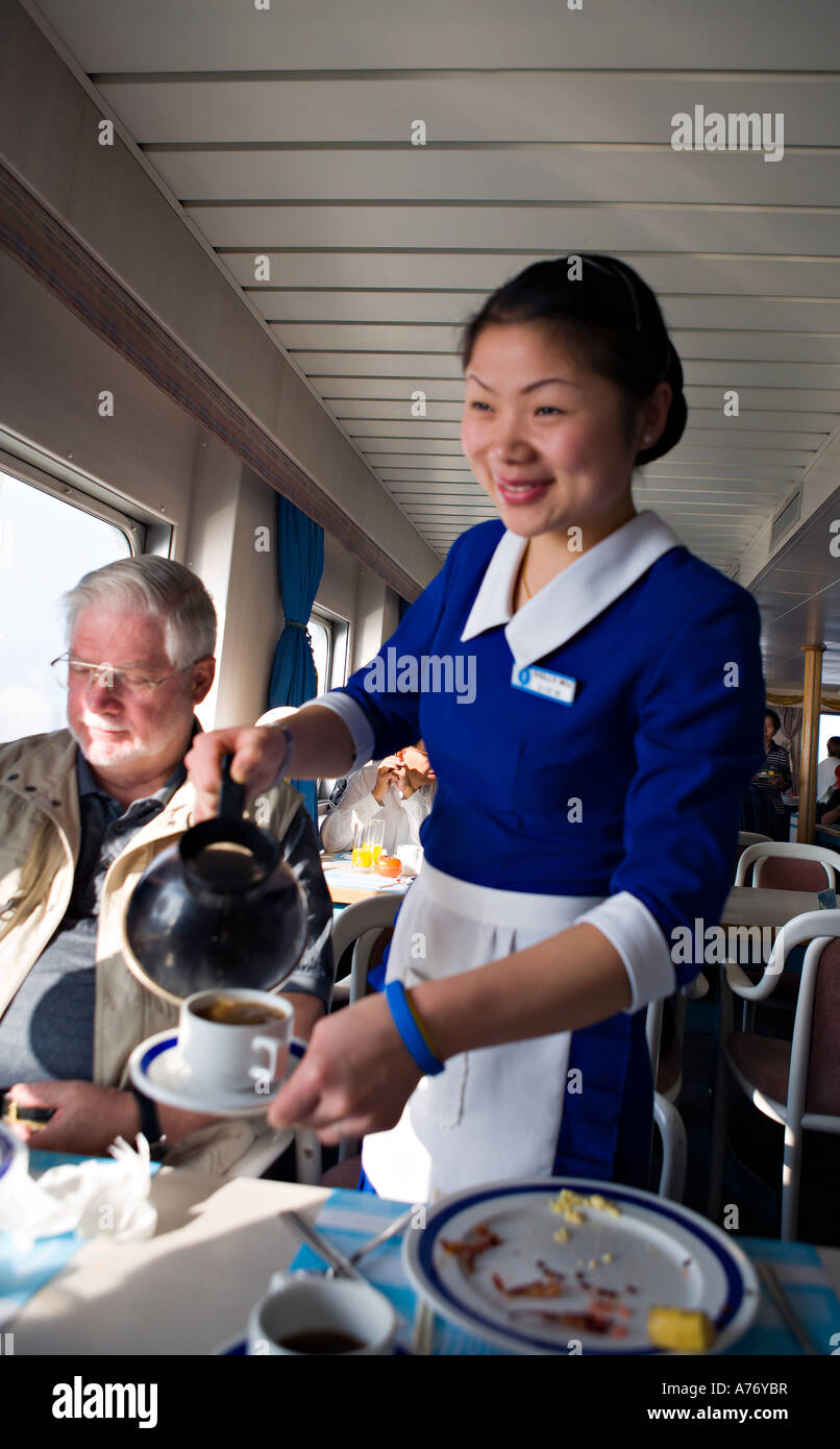 CHINA YANGTZE RIVER Cheerful Chinese waitress pours coffee for North ...