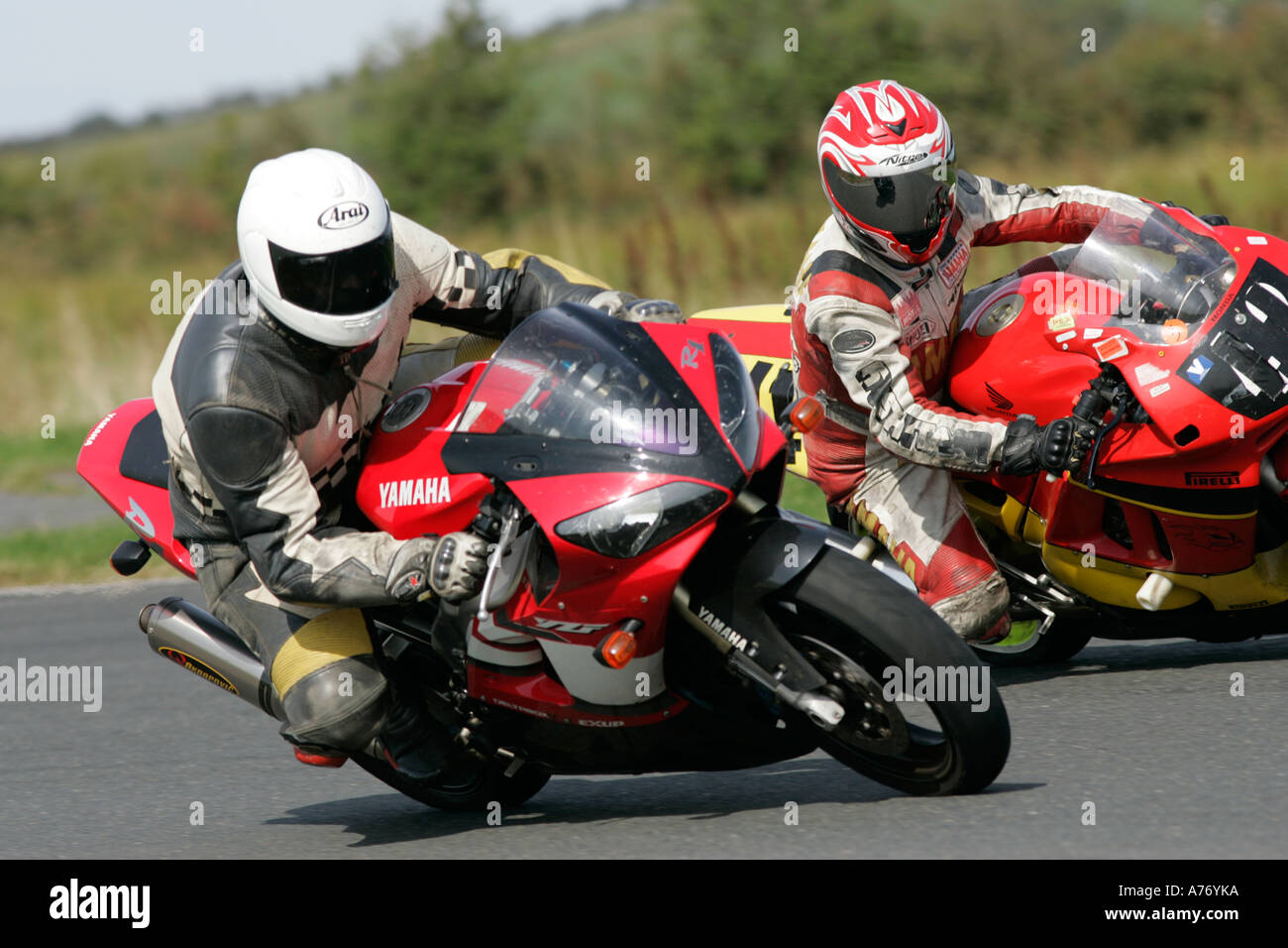 riders wearing leathers and helmets go through corner at speed during ...