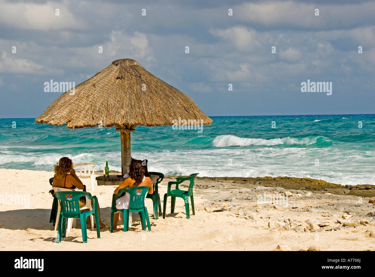 Two women sitting under a thatch palapa at the Punta Sur beach bar ...