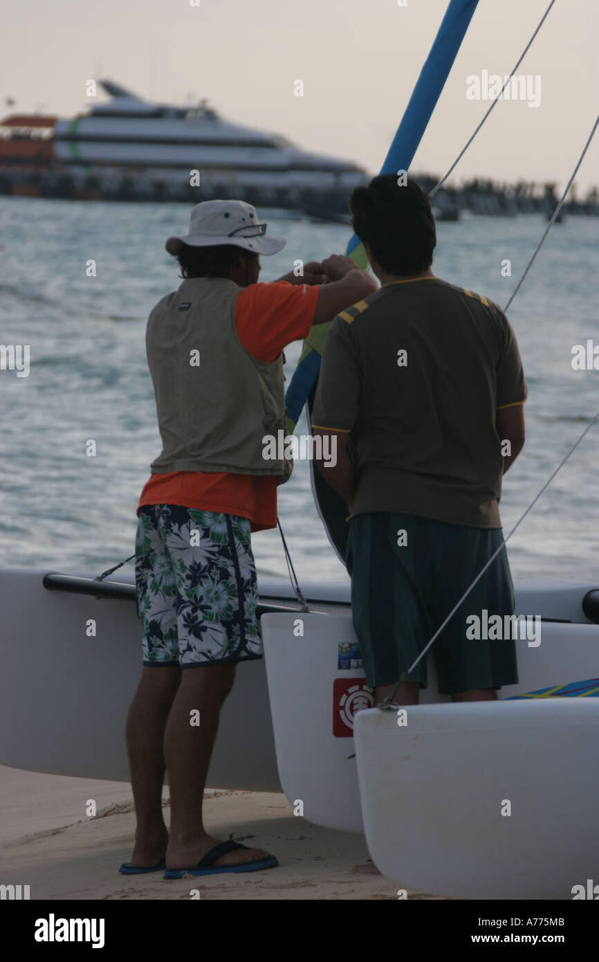 2 men prepare their boat for sailing in the crystal clear waters of the ...