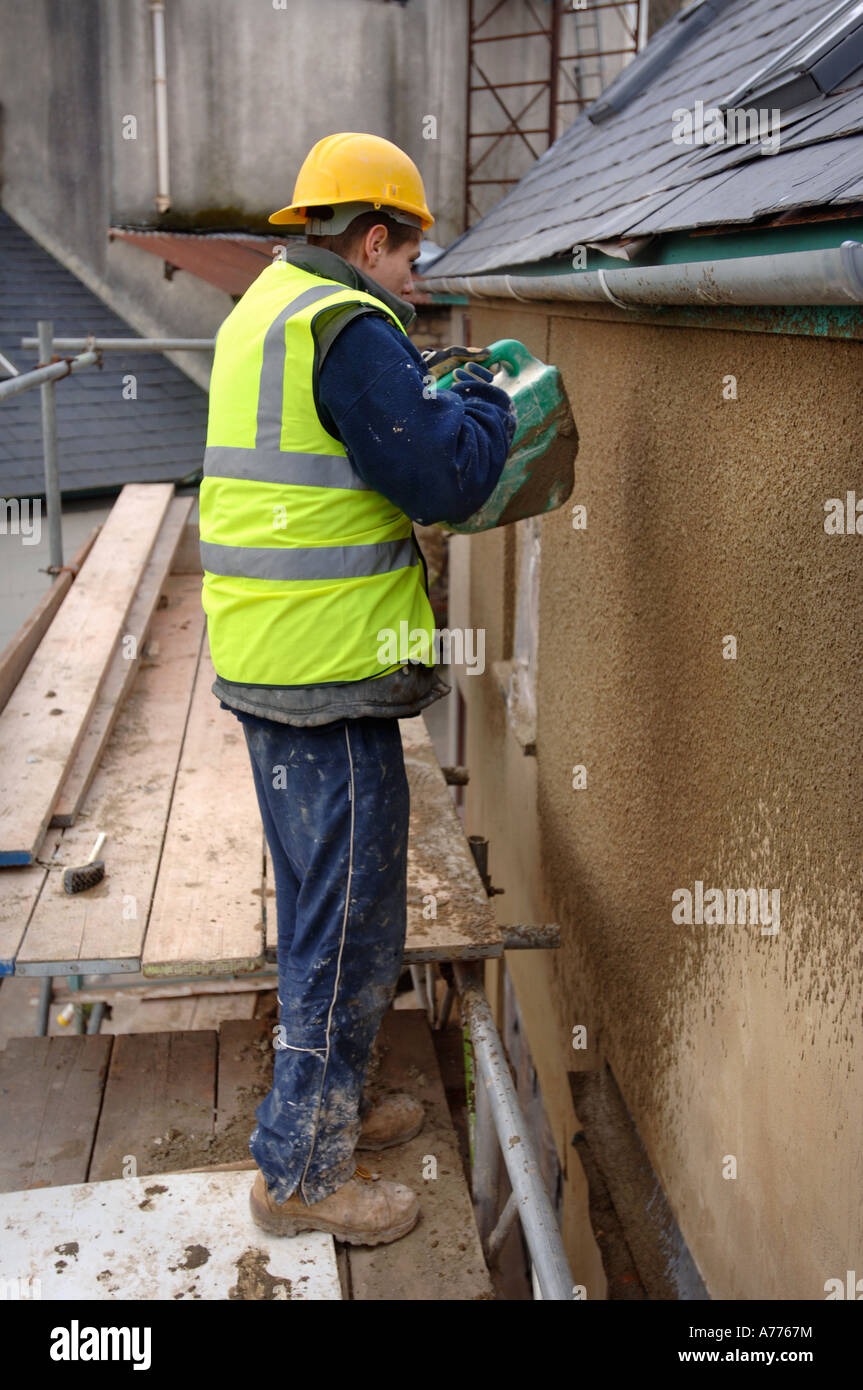 A PLASTERER RENDERING A ROUGHCAST FINISH AROUND NEW HARDWOOD CASEMENT ...