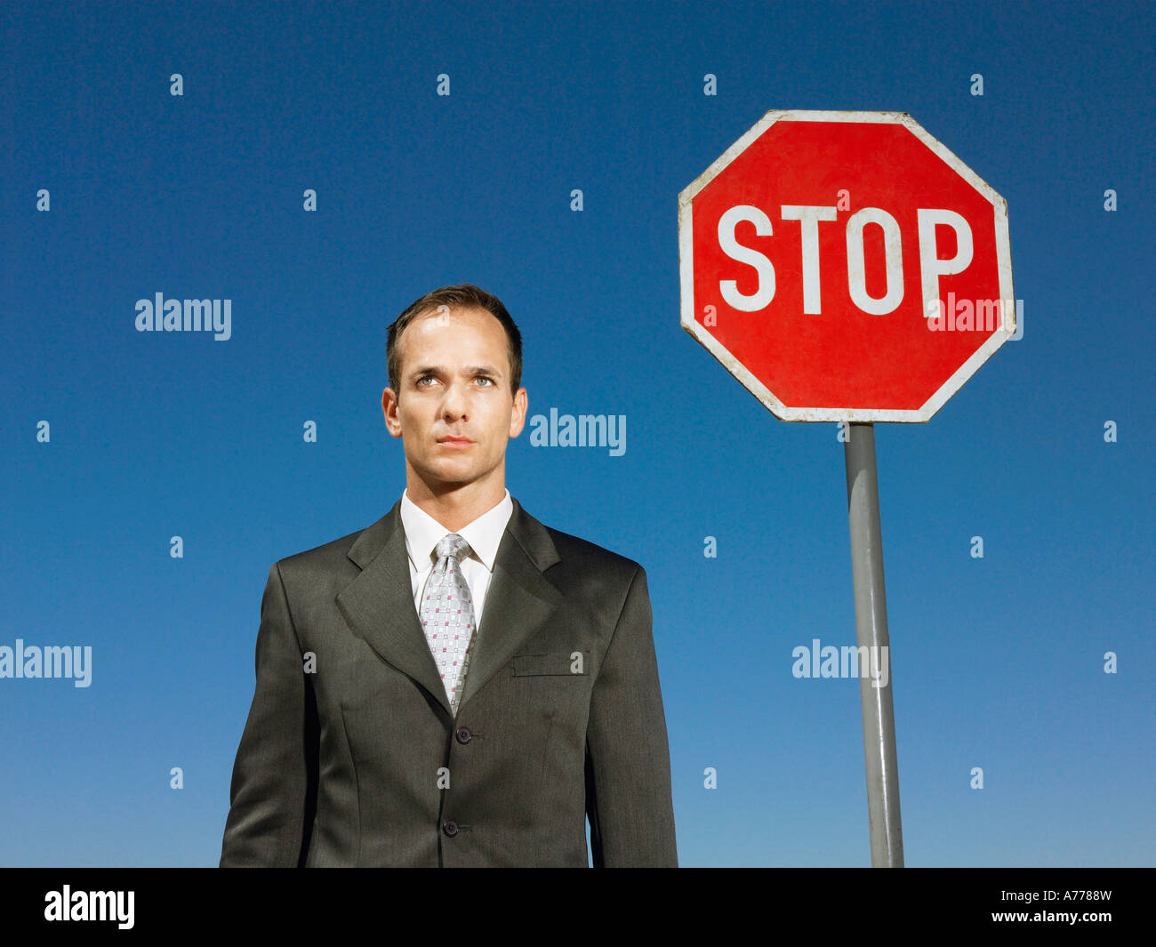 Businessman standing next to stop sign, half length Stock Photo - Alamy