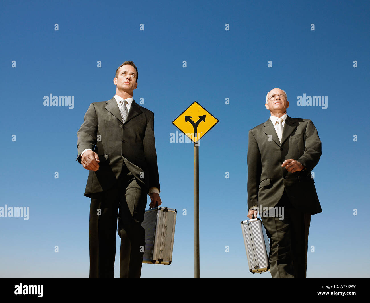 Two businessmen walking past road sign Stock Photo - Alamy