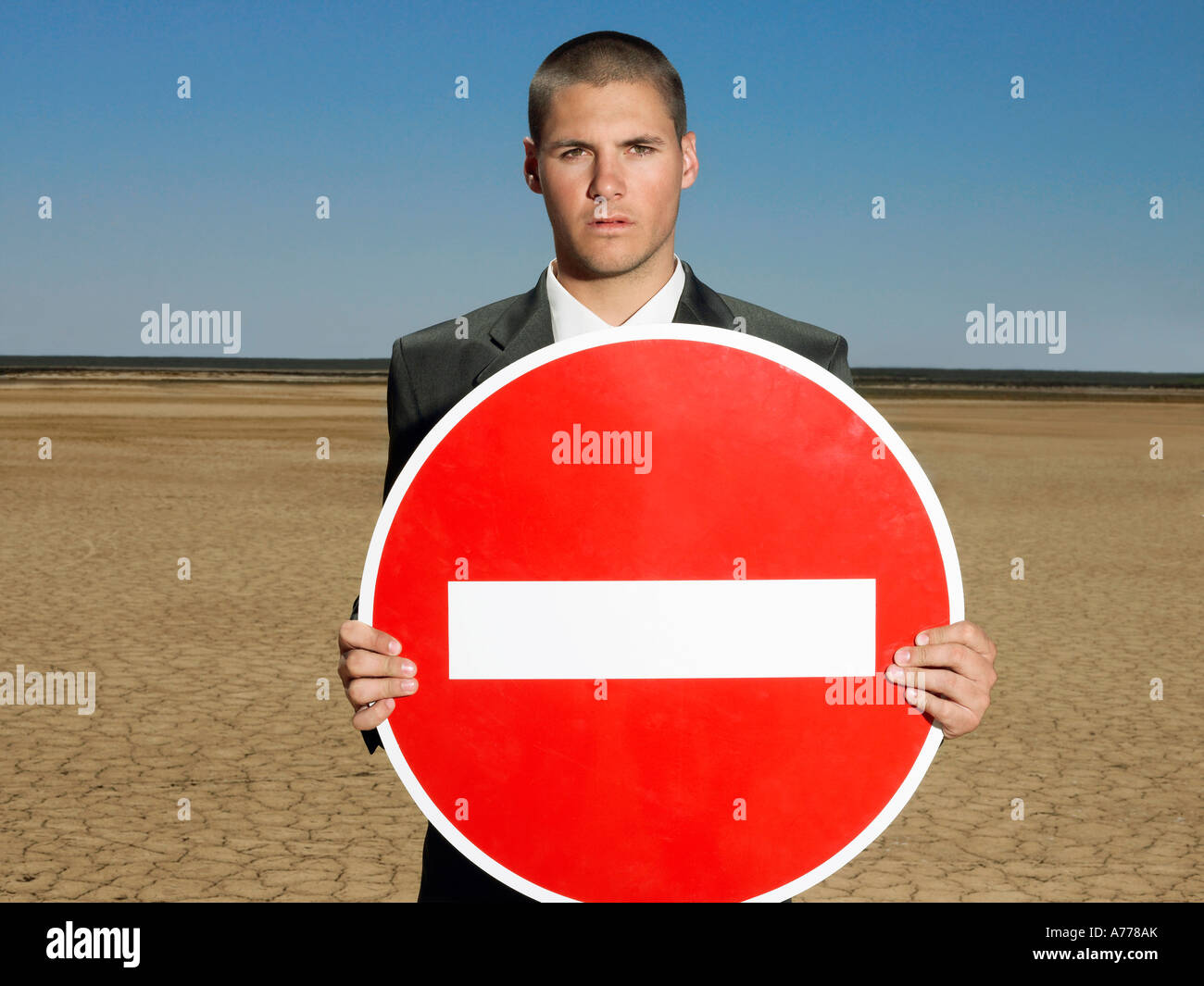 Businessman holding 'no entry' sign in desert, half length Stock Photo ...