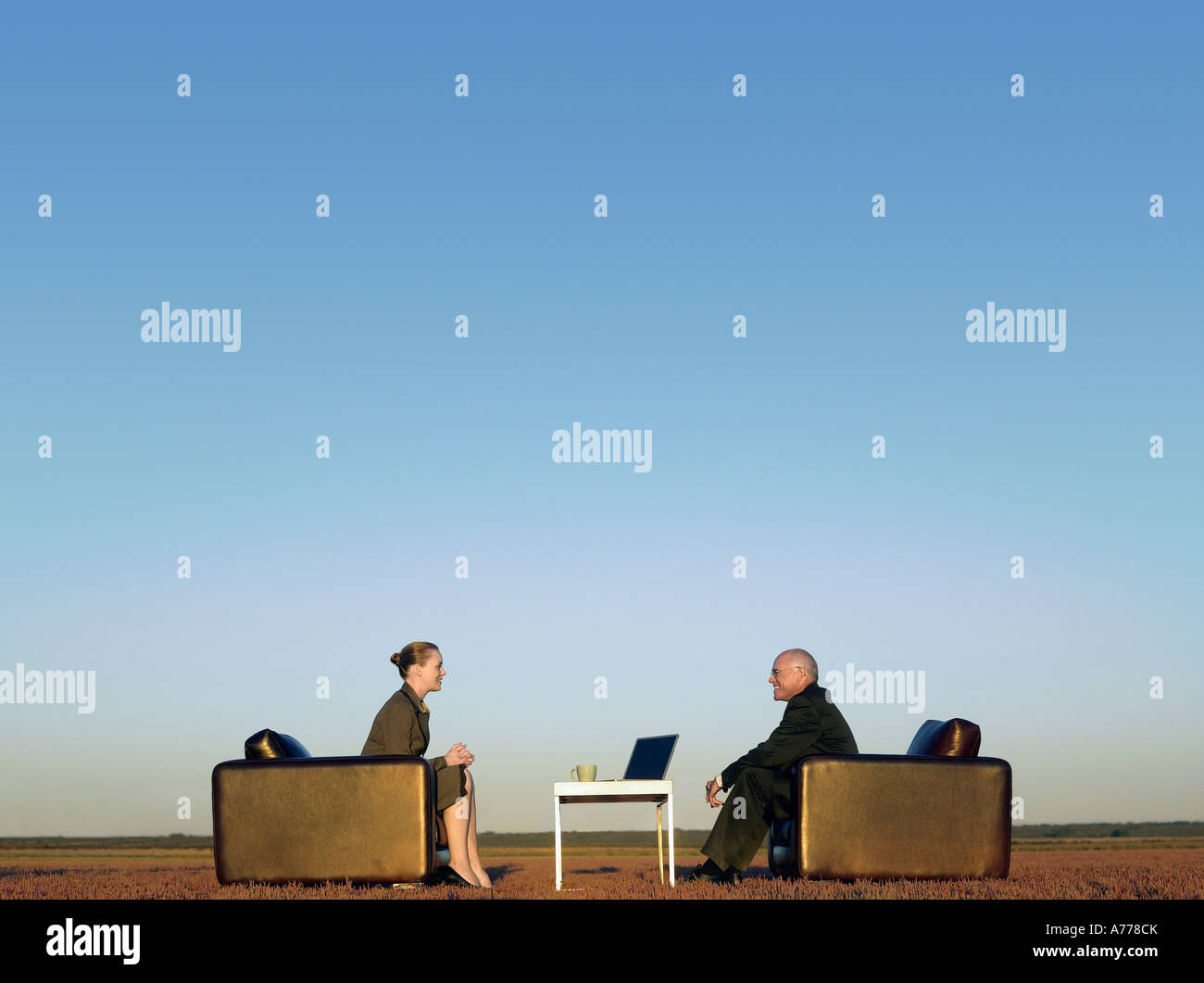 Business people sitting in chairs on open plain Stock Photo - Alamy