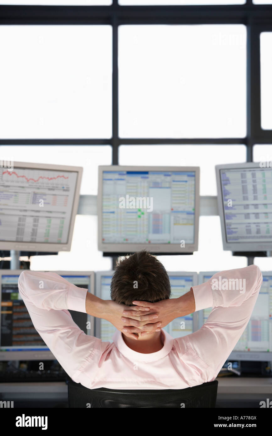 Businessman with Hands Behind Head, watching computer screens, back ...