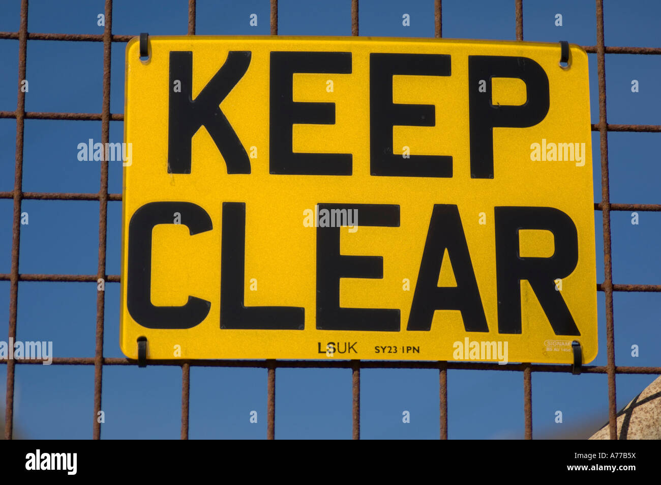Keep Clear warning sign on wire fence outside building site - black ...