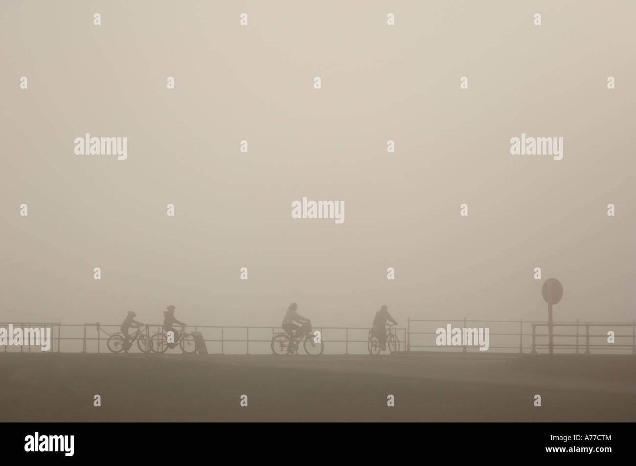 four people in a Family group cycling in the fog Stock Photo - Alamy