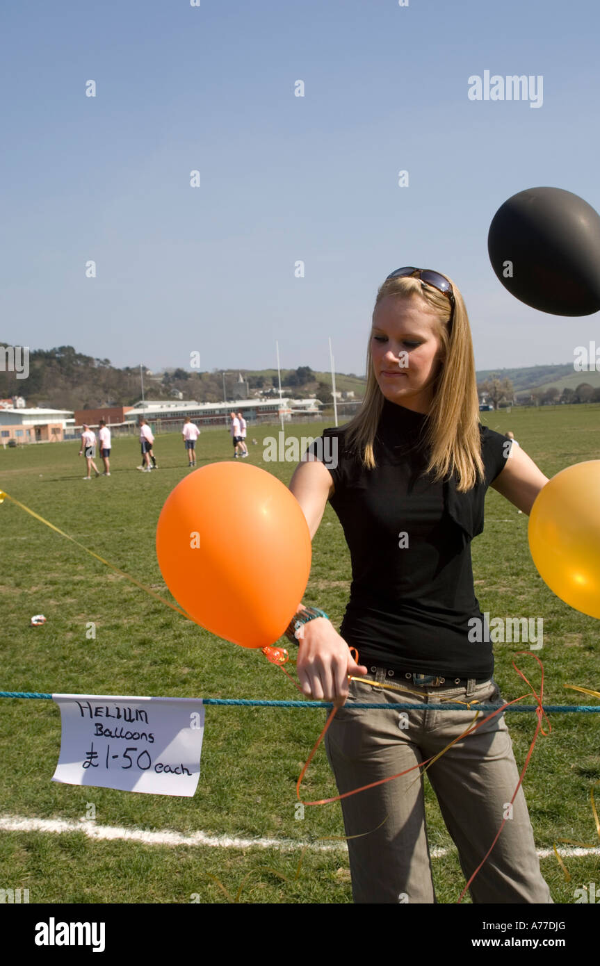 young woman selling orange and yellow helium filled balloons for ...