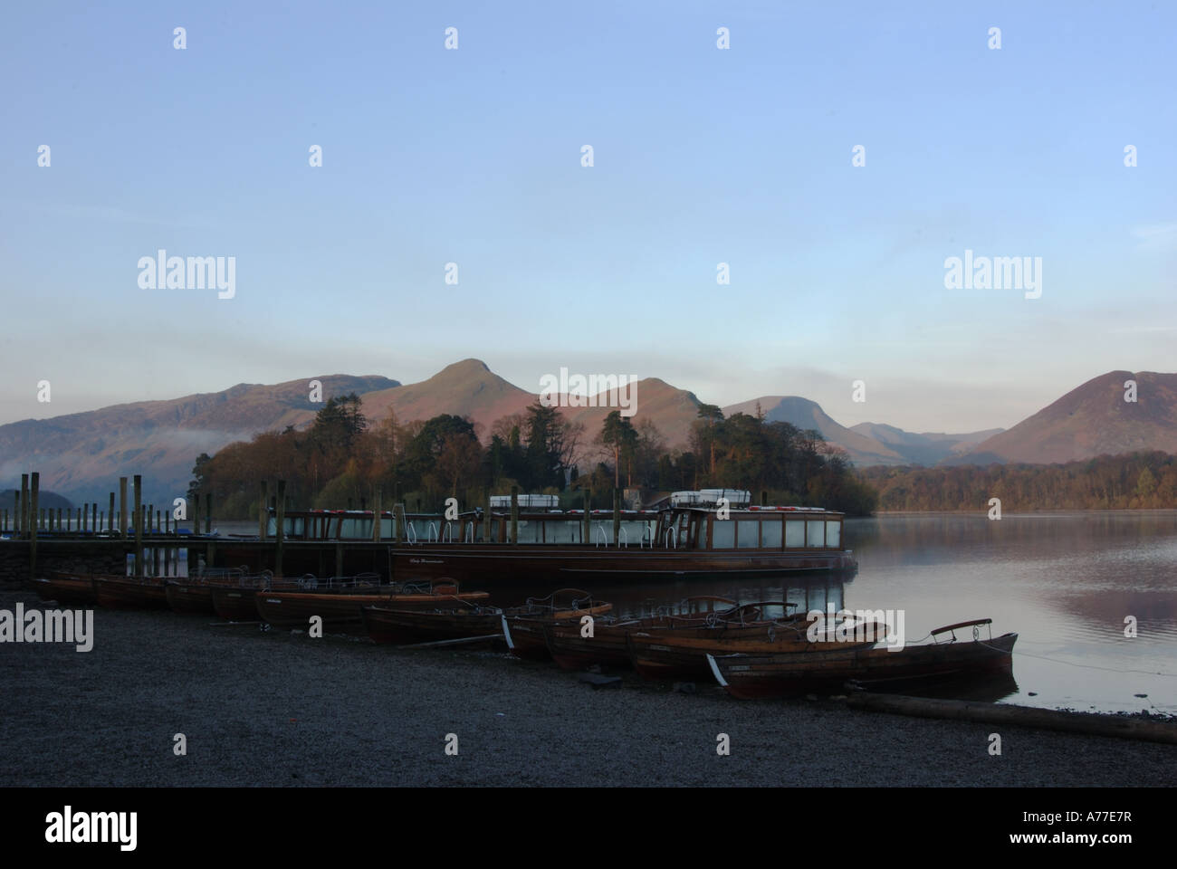 still water and boats at sunrise with mist on the lake Derwent Water ...