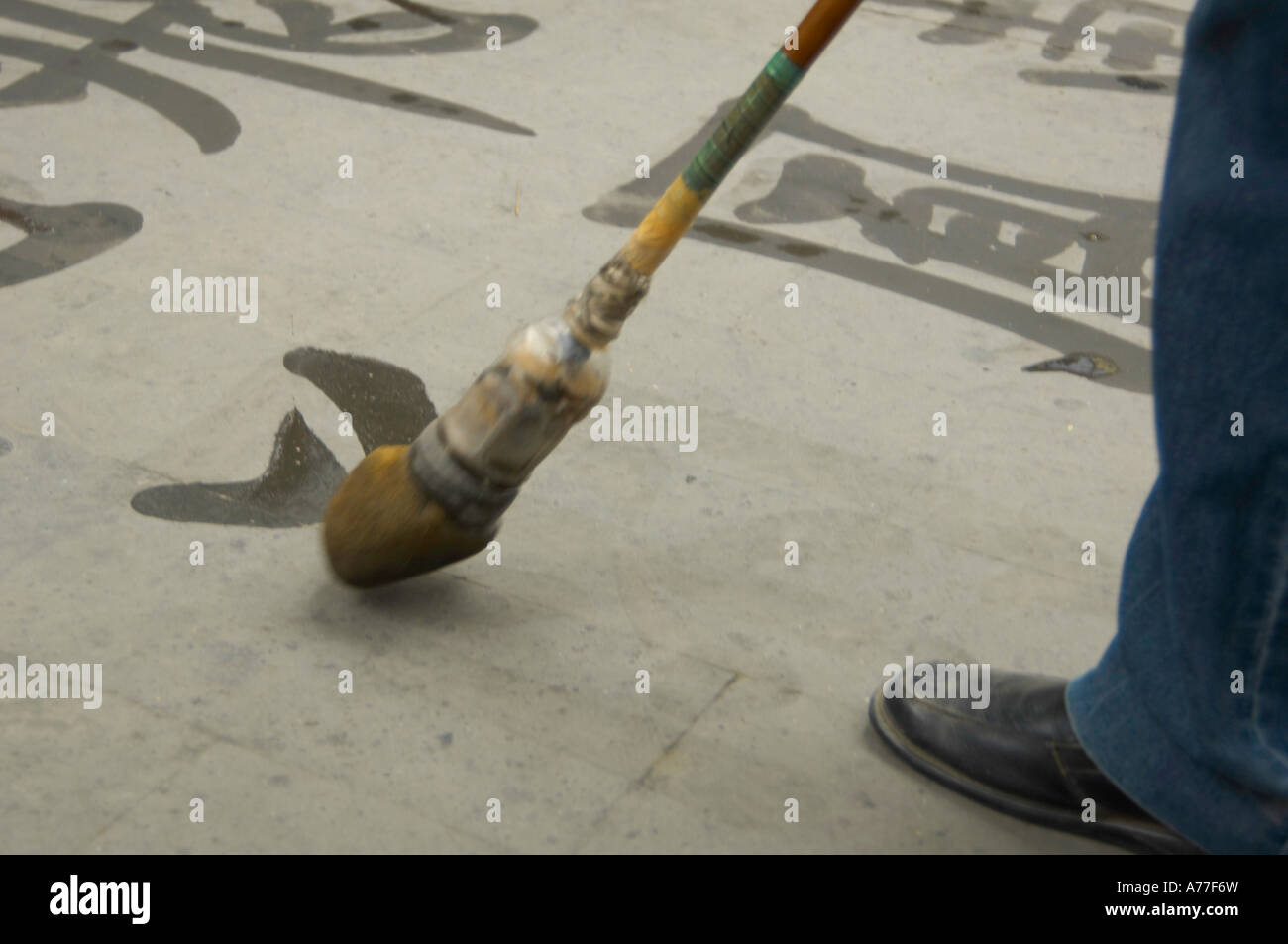 man writes Chinese characters on walk using long handled brush and ...
