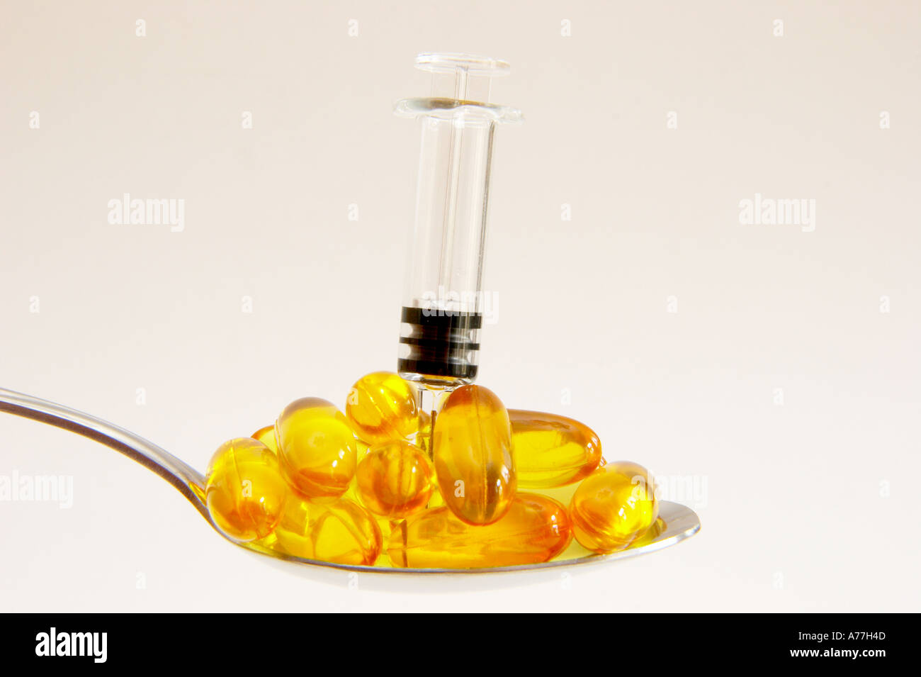 Small syringe on a spoon with oil capsules Stock Photo - Alamy