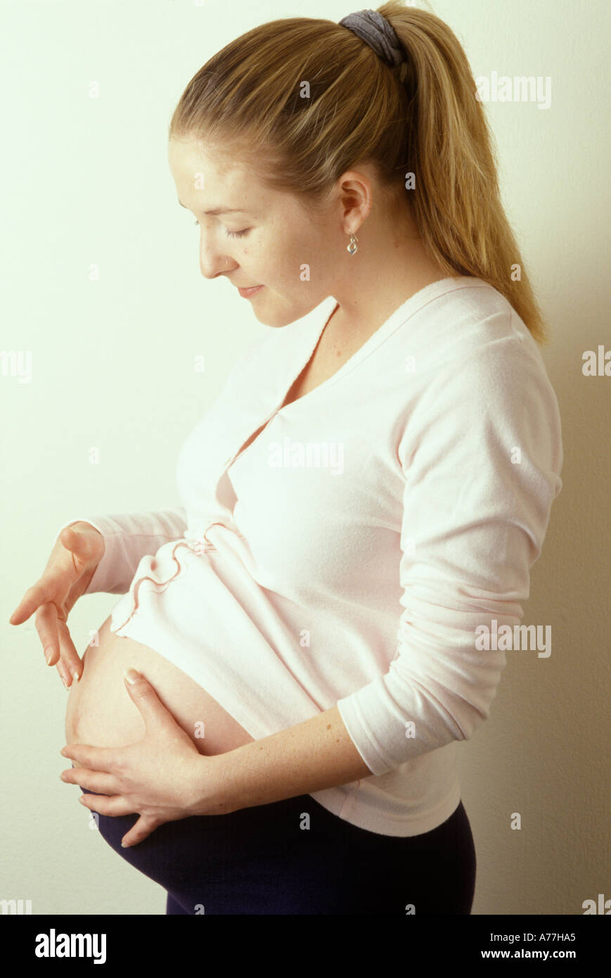 Pregnant woman rubbing her bump as if talking to her baby Stock Photo ...