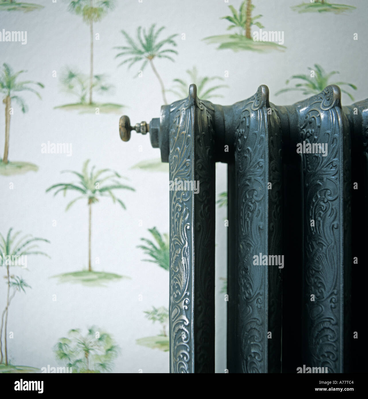 Victorian radiator against a wall covered with wallpaper with palm tree ...