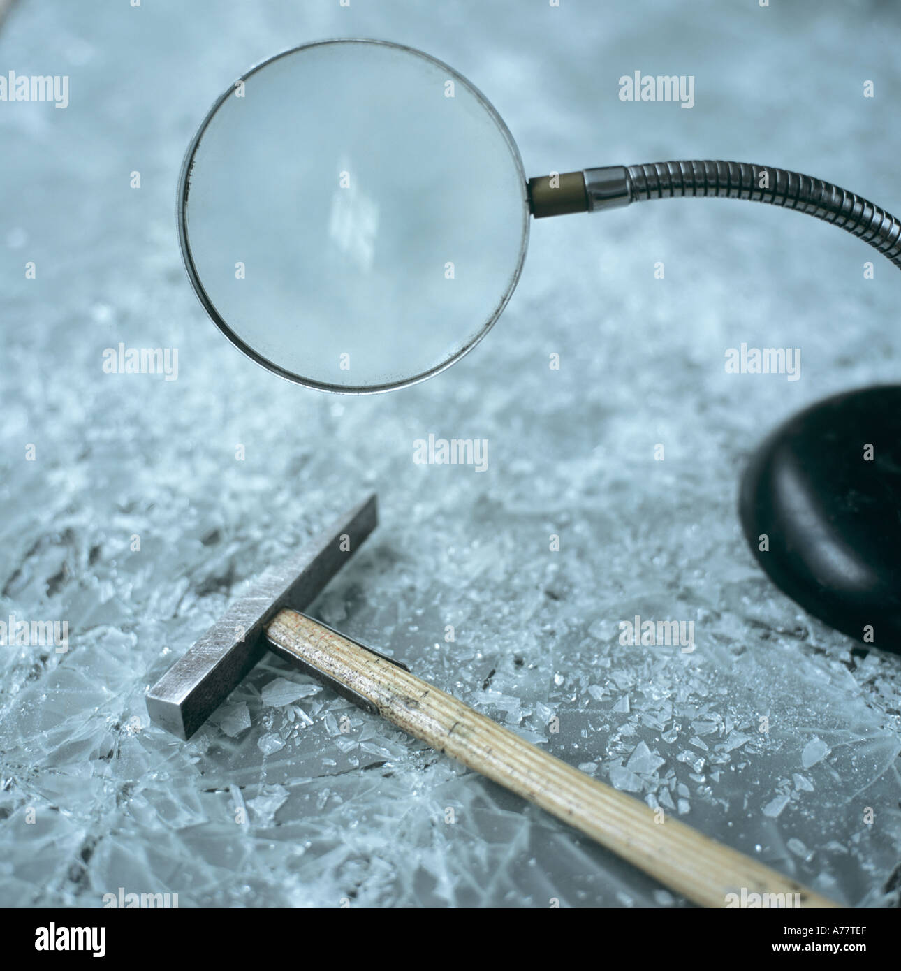 working tools a small hammer and magnifying glass on broken glass panel ...