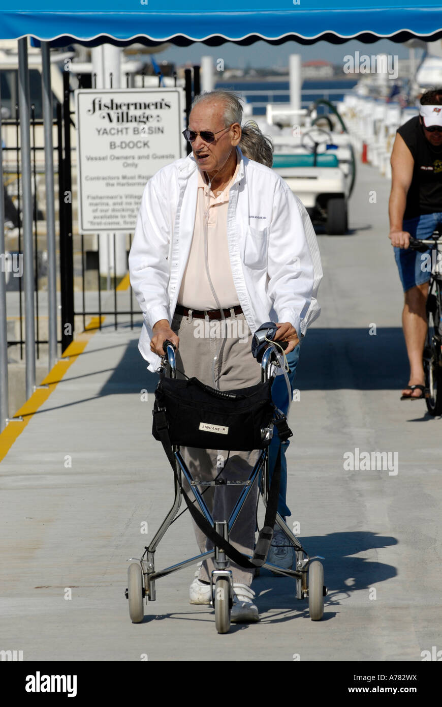 Senior couple walking with the man using a walking aid with wheels ...