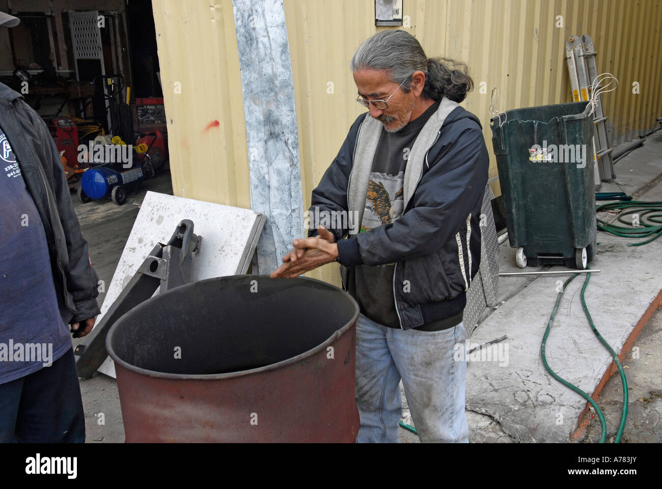 Homeless man warms hands over a fire built in a metal barrel Stock ...