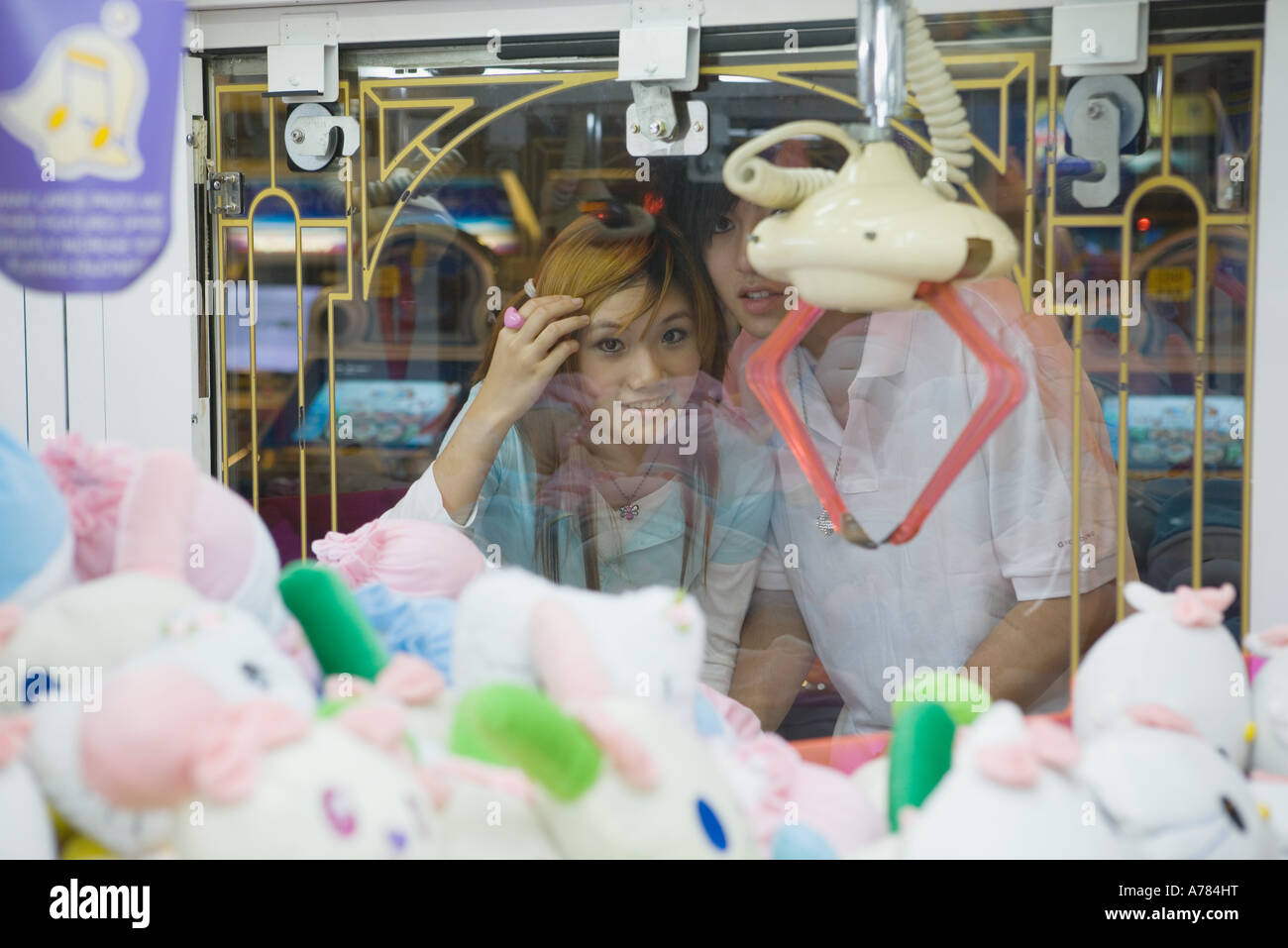 Teenage couple looking at toy grabbing game in video arcade Stock Photo ...