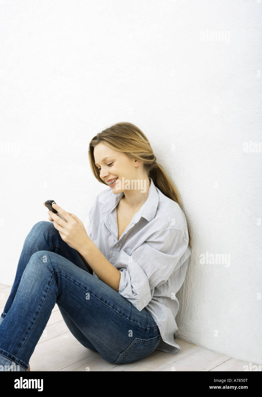Teenage girl using cell phone, sitting on floor Stock Photo - Alamy