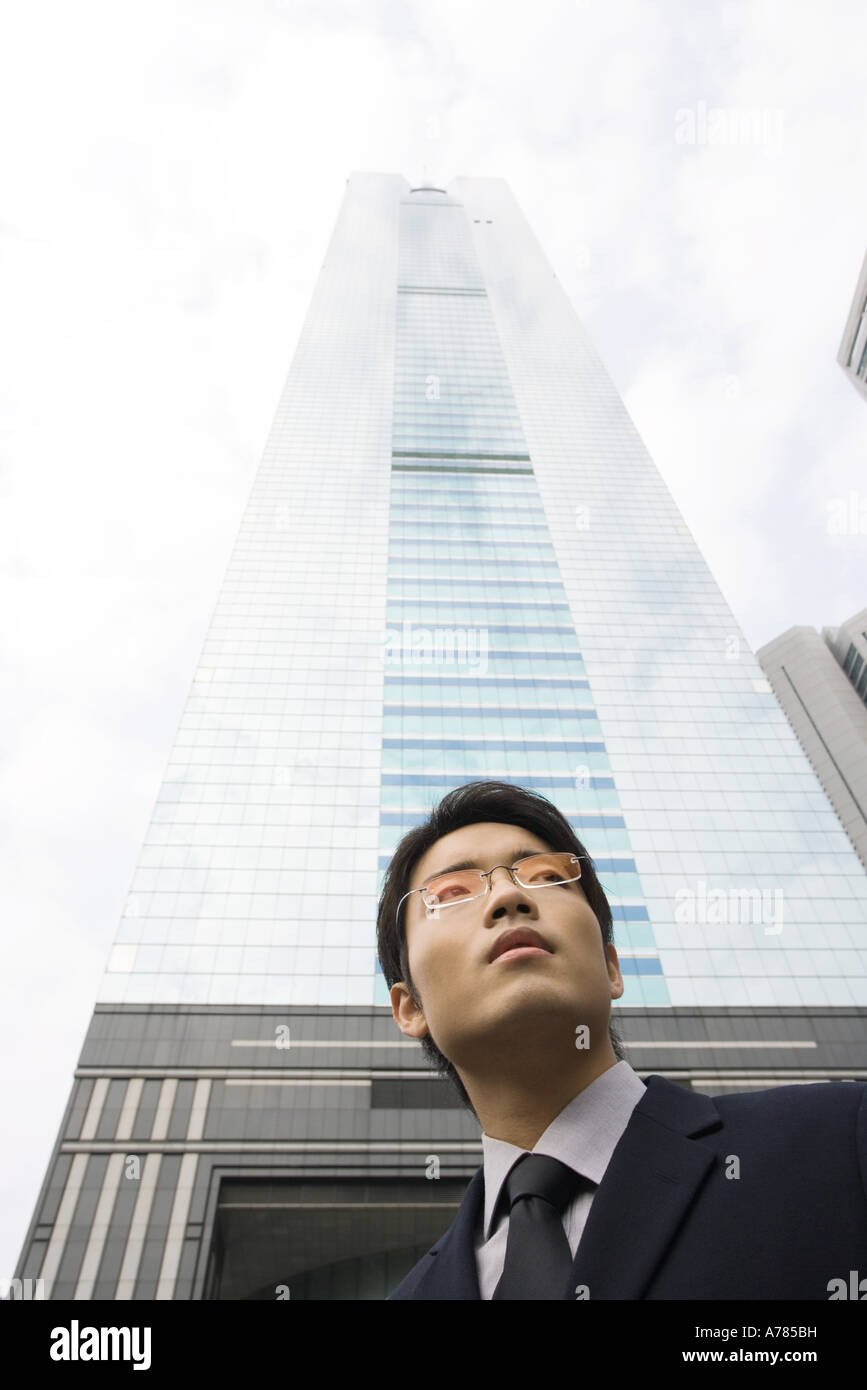 Young businessman standing in front of skyscraper, low angle view Stock ...