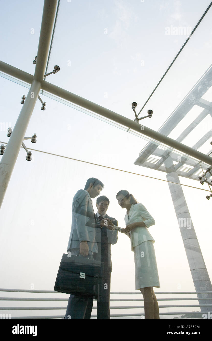 Three young executives talking in covered walkway, low angle view Stock ...