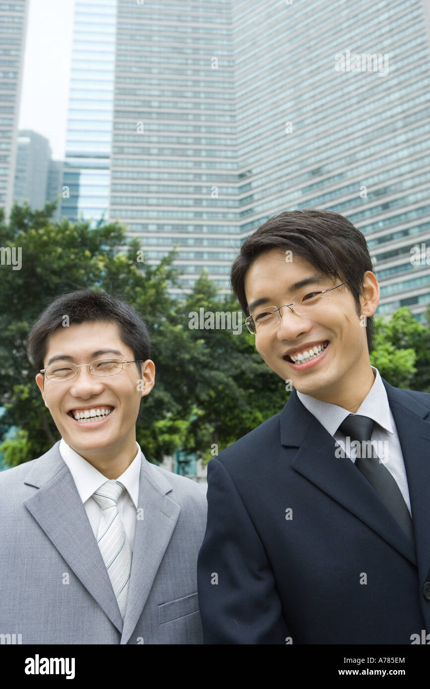 Two young businessmen, laughing, office building in background Stock ...