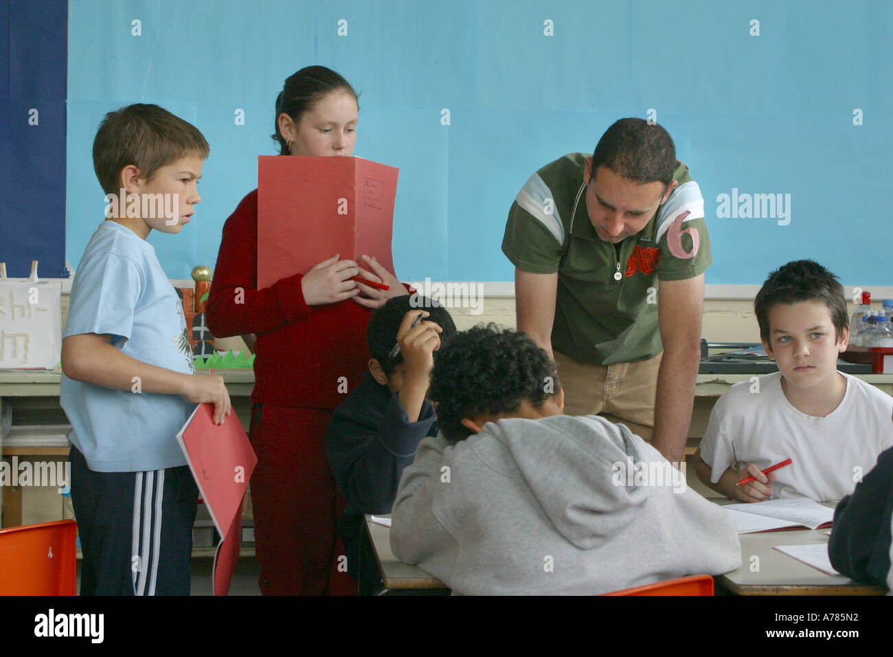 Teacher assisting primary school children with their work Stock Photo ...