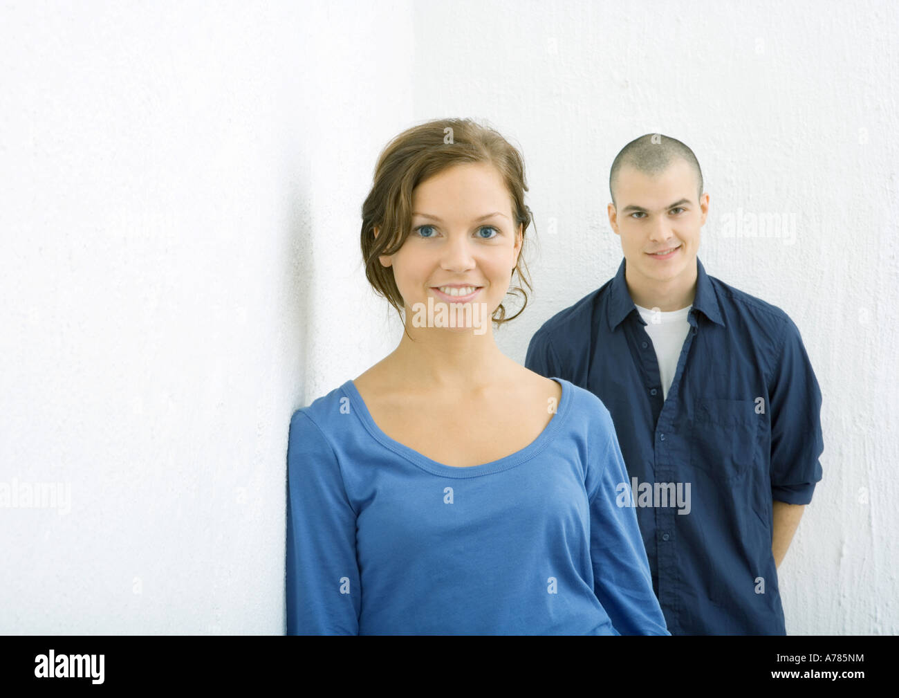 Young woman smiling at camera, young man behind her smirking Stock ...