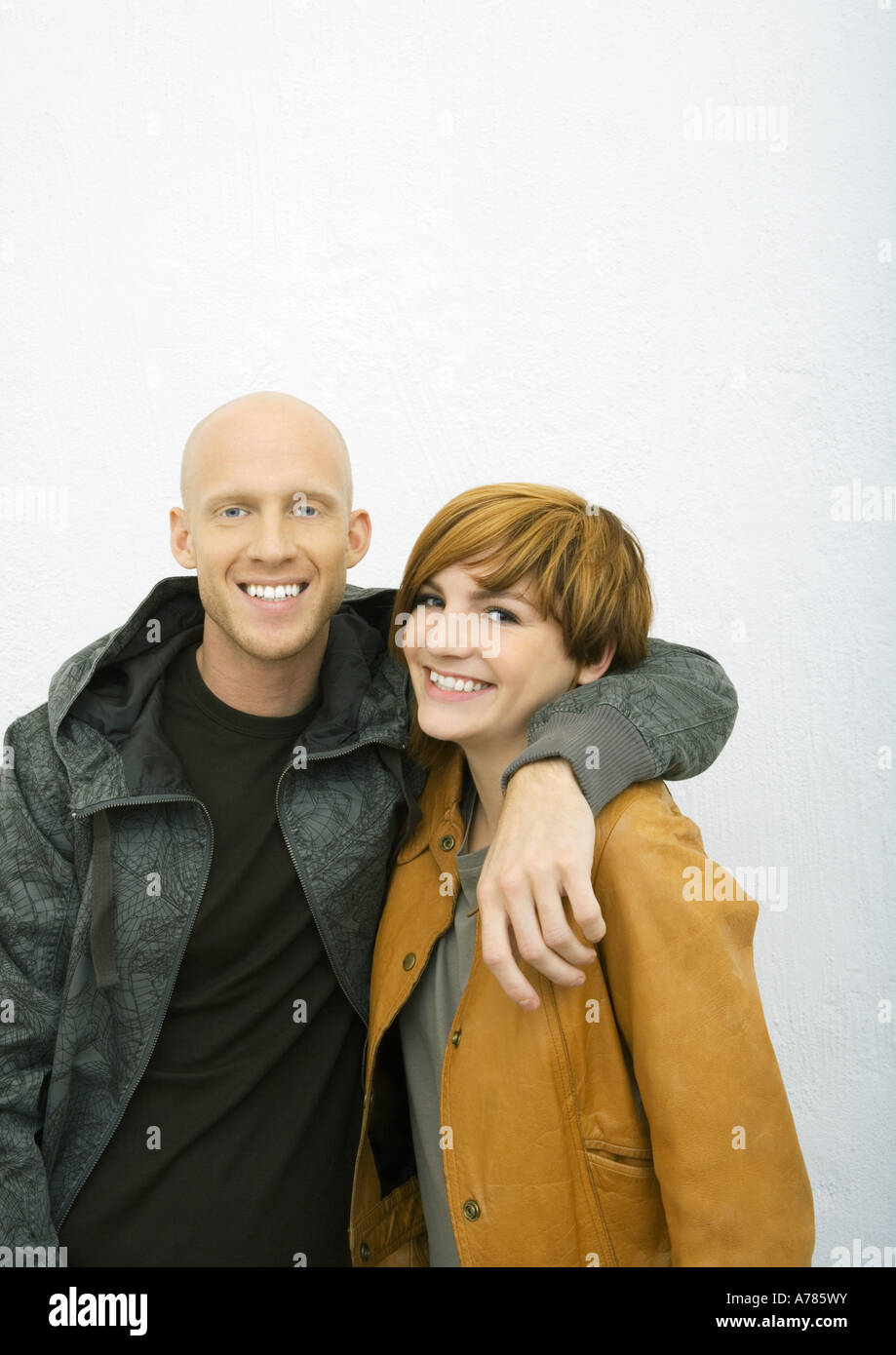 Young couple, man with arm around woman's shoulders, both smiling at ...