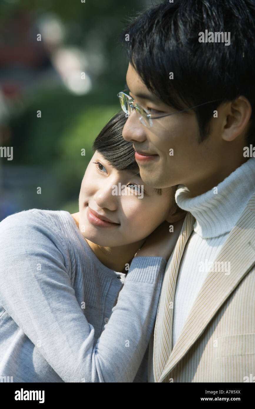 Young couple, woman leaning head on man's shoulder, both looking away ...