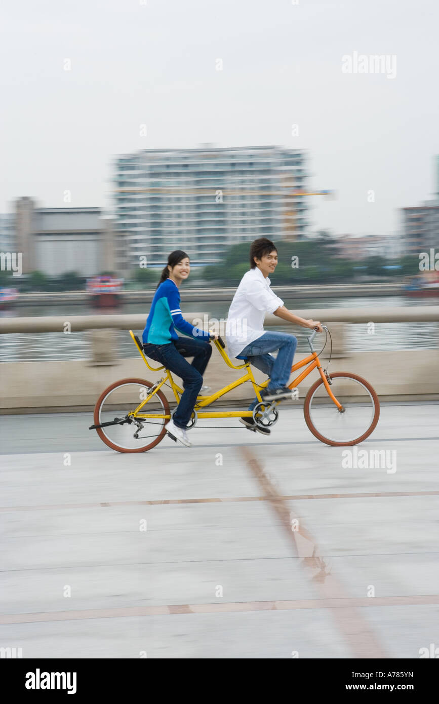 Young couple riding tandem bicycle Stock Photo - Alamy