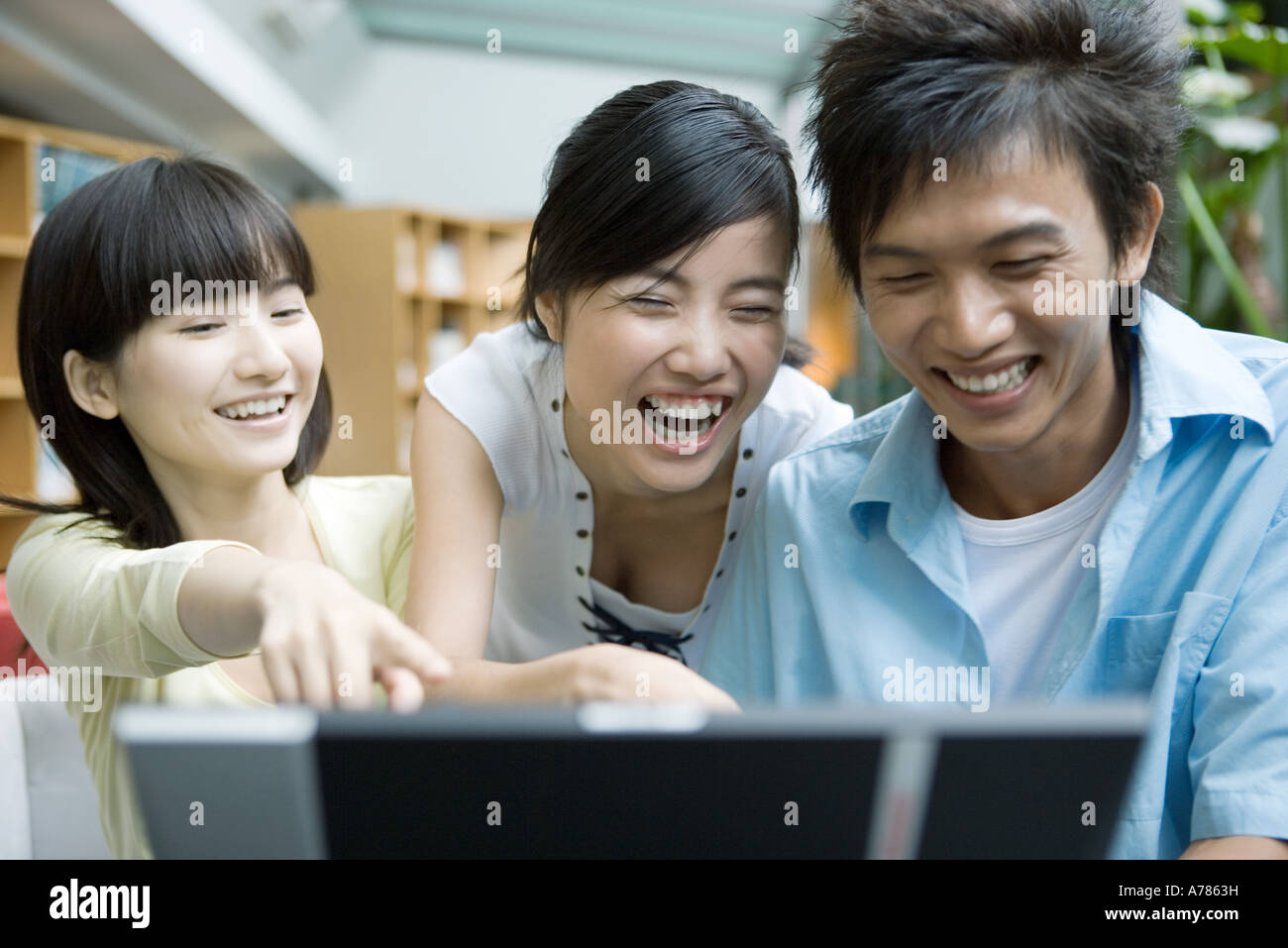 Three friends using computer, laughing Stock Photo - Alamy