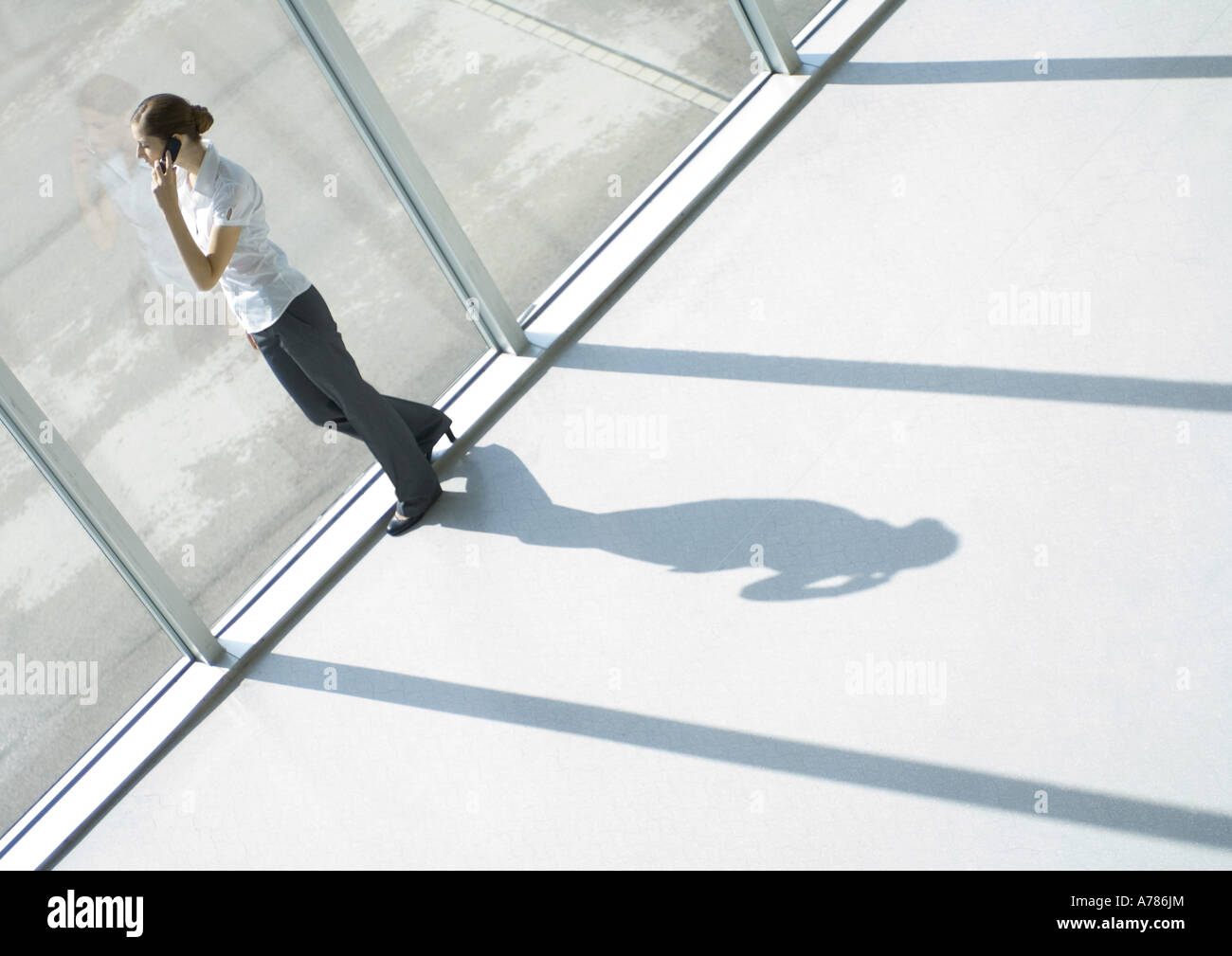 Young woman using cell phone by window, full length, high angle view ...