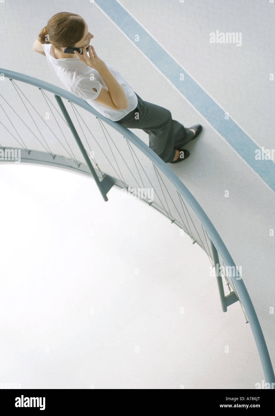 Woman leaning against railing, using cell phone, full length, high ...