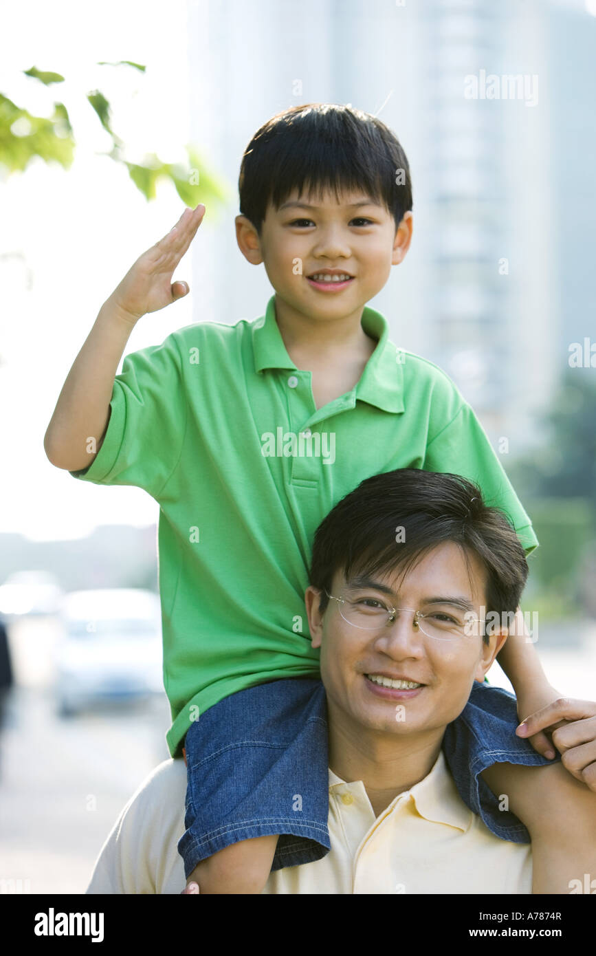 Man carrying son on shoulders, boy making gesture Stock Photo - Alamy