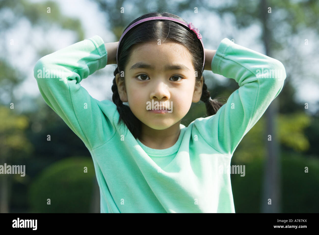 Girl standing with hands behind head, looking at camera Stock Photo - Alamy