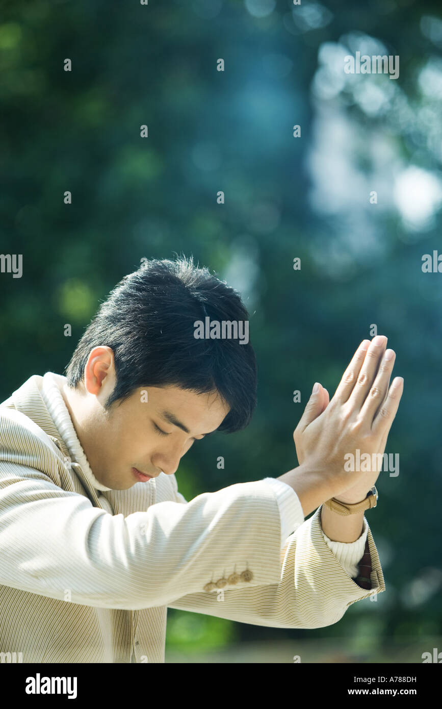 Man holding hands in prayer and bowing head Stock Photo - Alamy