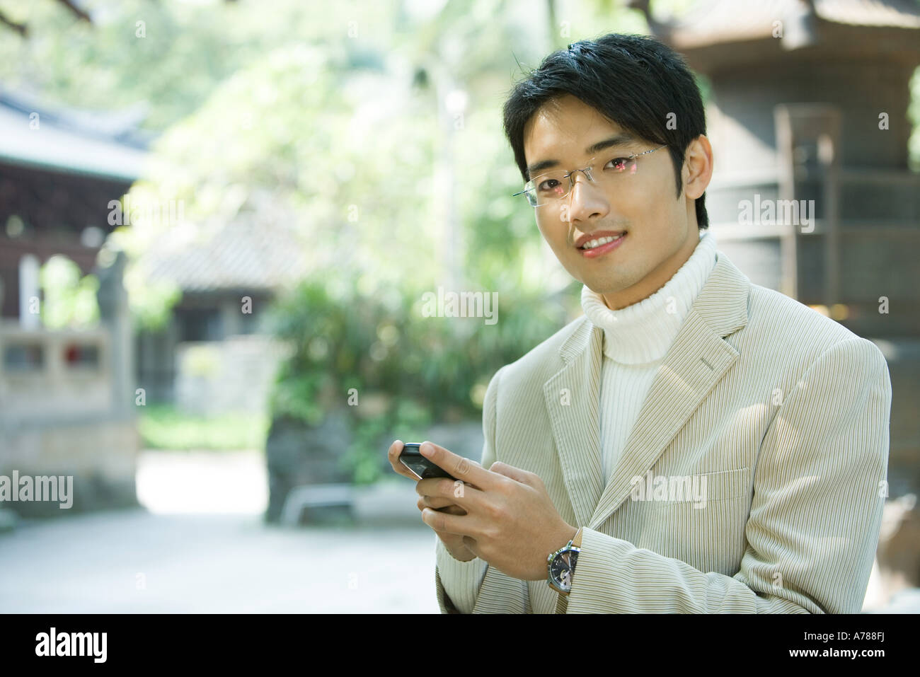 Man holding cell phone, smiling at camera Stock Photo - Alamy