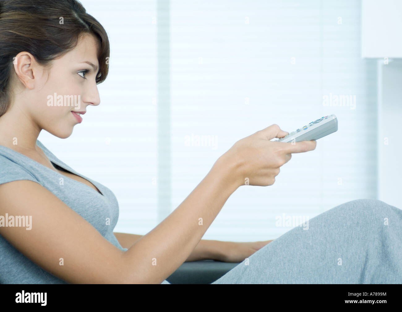 Young woman pointing remote control, profile Stock Photo - Alamy