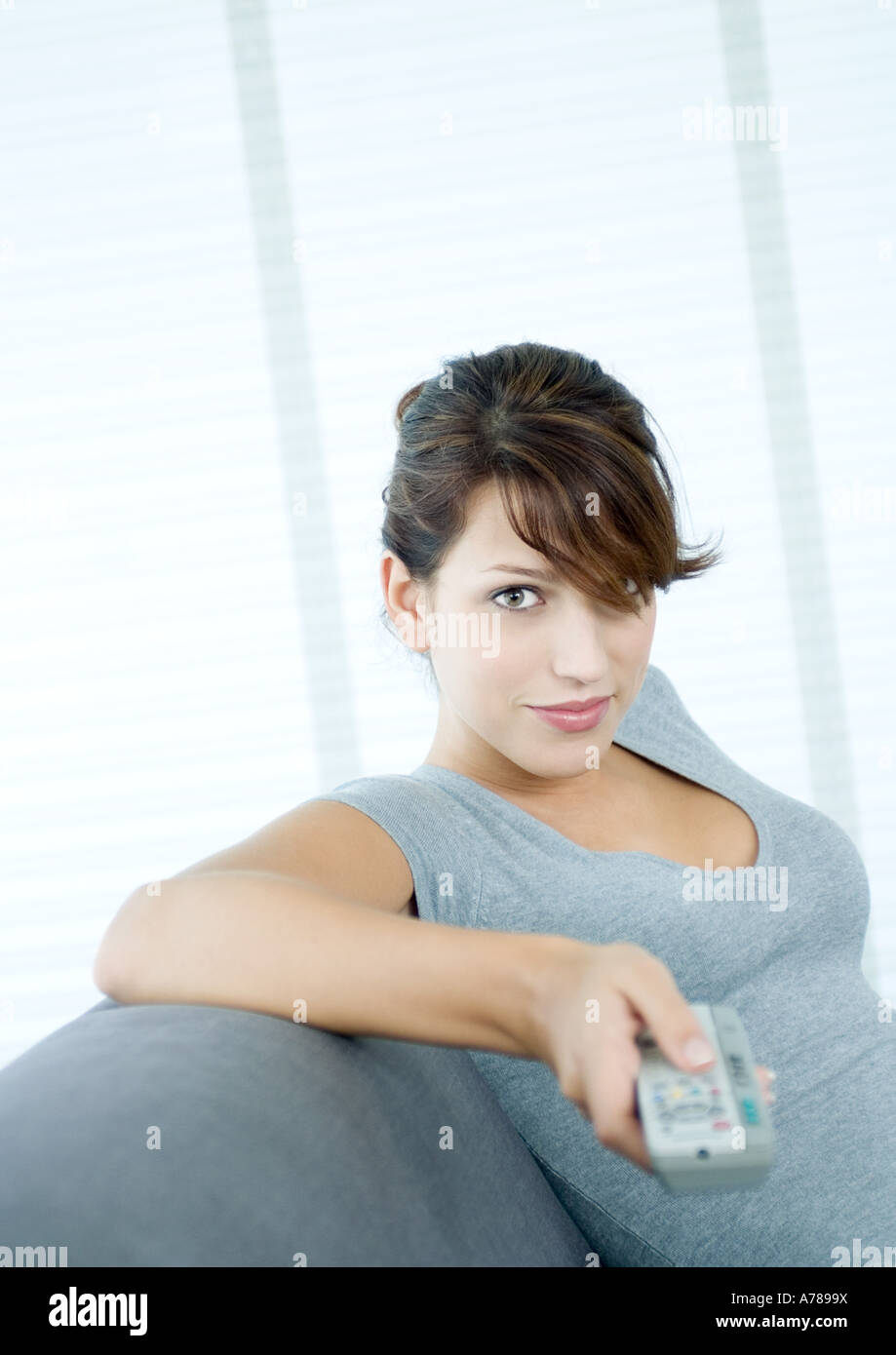 Young woman pointing remote control, smiling at camera Stock Photo - Alamy