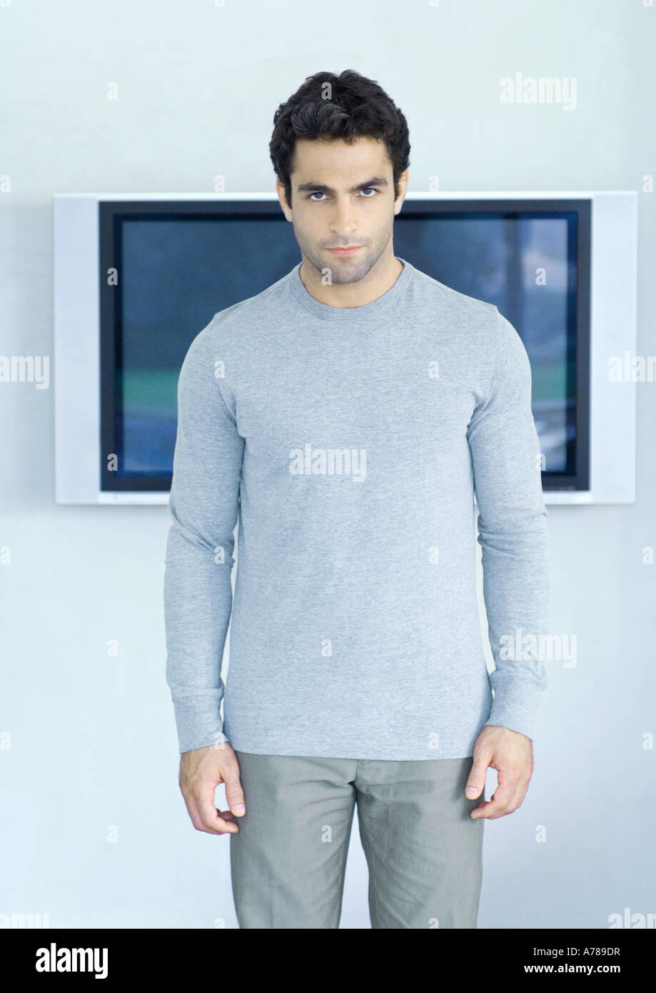 Man standing in front of wide screen TV, looking at camera Stock Photo ...