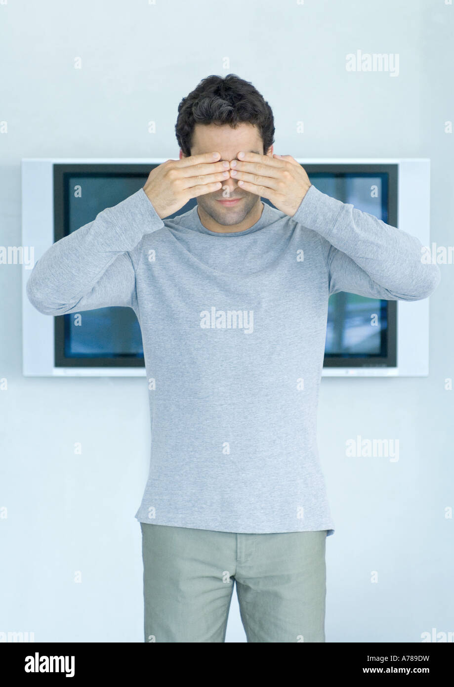 Man standing in front of wide screen TV, hands over eyes Stock Photo ...