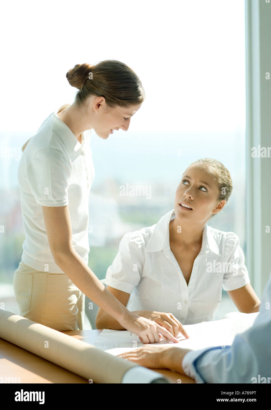 Two women discussing blueprints in office Stock Photo - Alamy