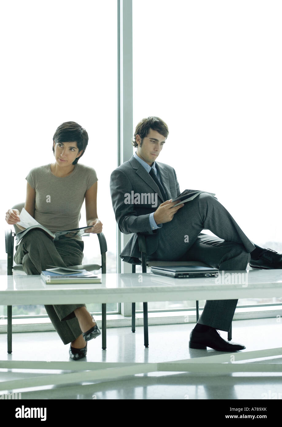 Two young professional adults sitting in waiting room Stock Photo - Alamy