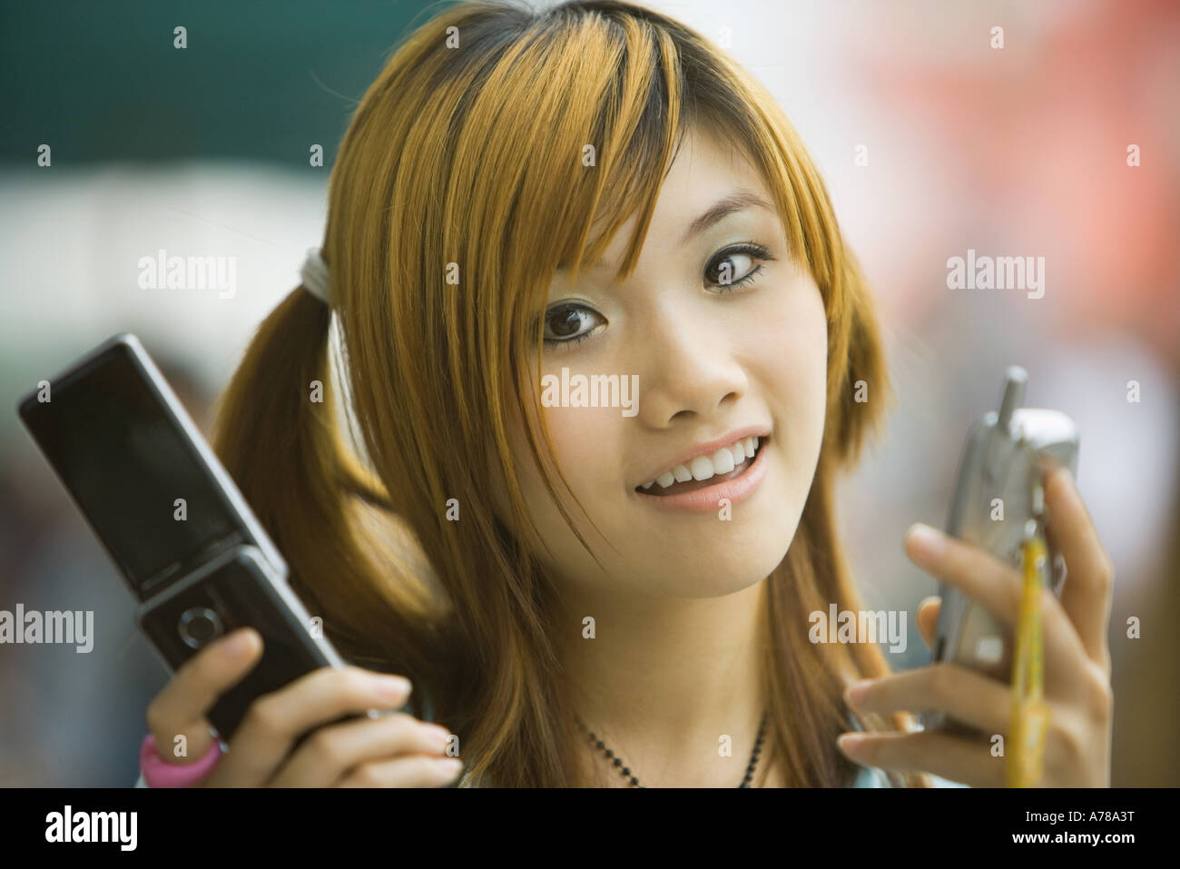 Young woman holding two cell phones, looking at camera Stock Photo - Alamy