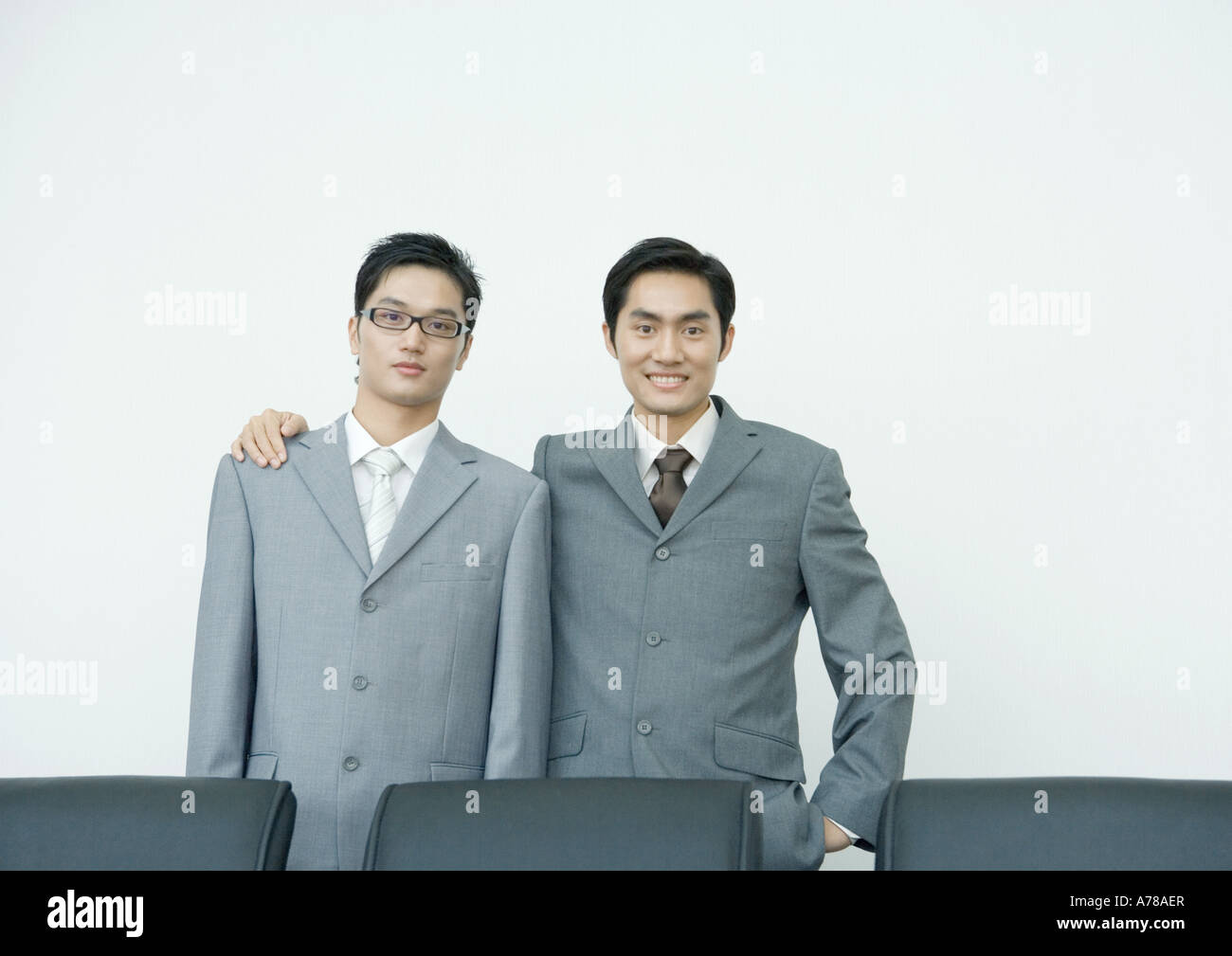 Two businessmen, one standing with arm around the other's shoulders ...