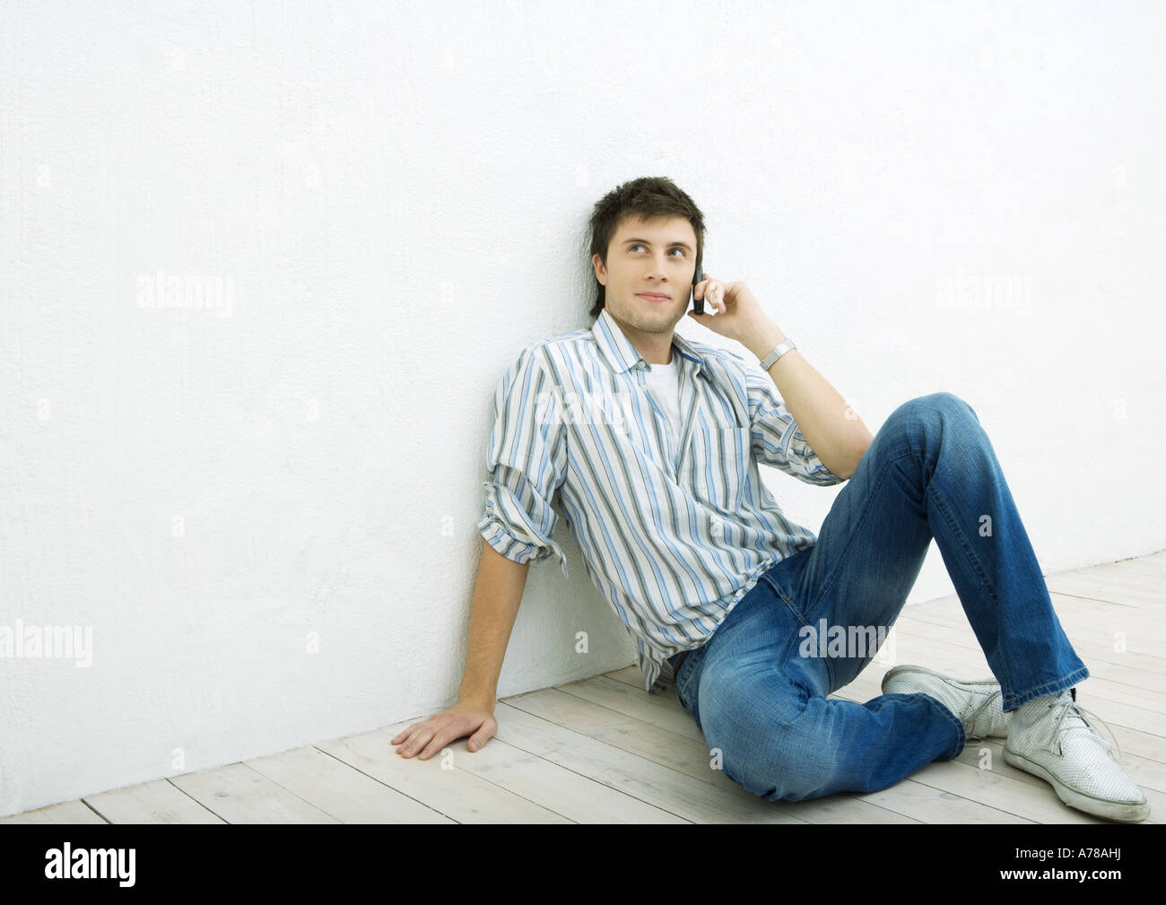 Young man sitting on floor, using cell phone Stock Photo - Alamy