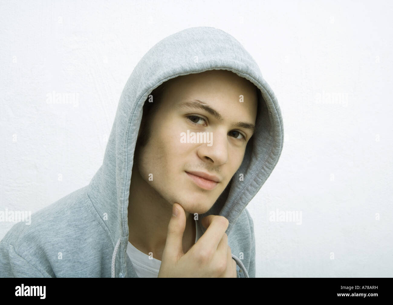 Young man scratching chin, wearing hood, portrait Stock Photo - Alamy